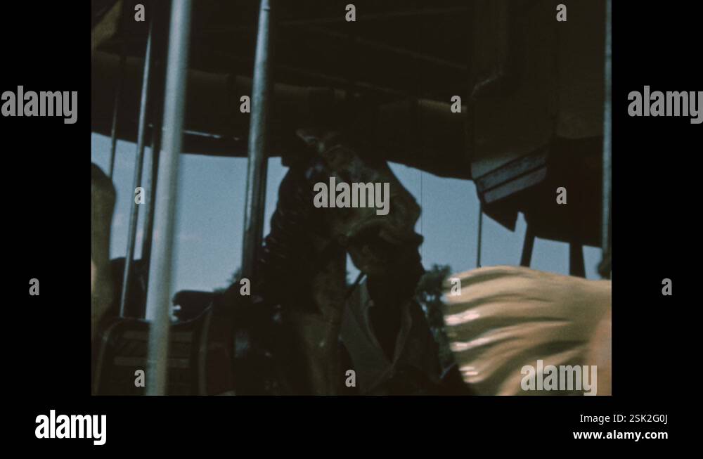 1950s: Carousel horses start to spin. Carousel. Man stands before a ...