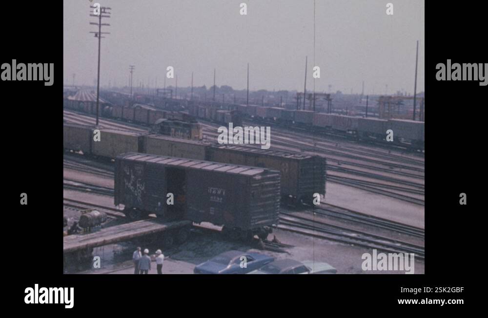 1970s: HIgh angle of trains in rail yard, workers by tain car in ...