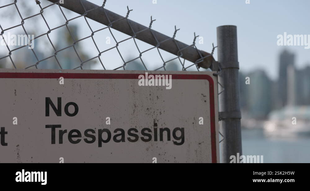 No Trespassing sign on chain link fence with city scape in background ...