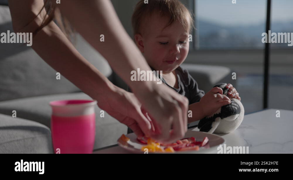 Toddler eats fruit off plate while watching TV - medium shot Stock ...