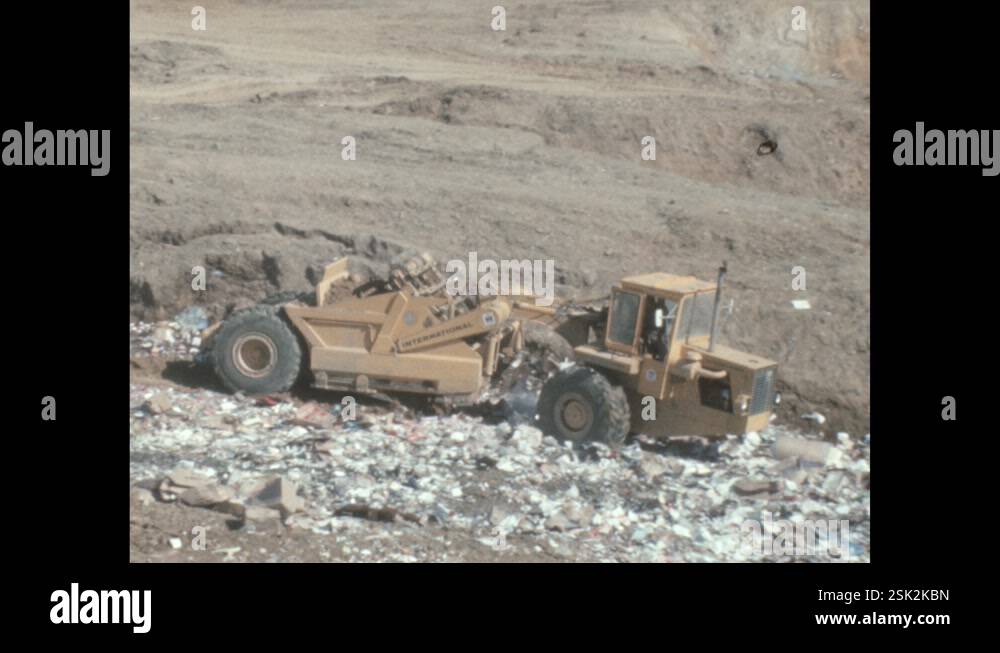 1960s: Truck pulling trailer, dumps dirt over garbage in landfill Stock ...