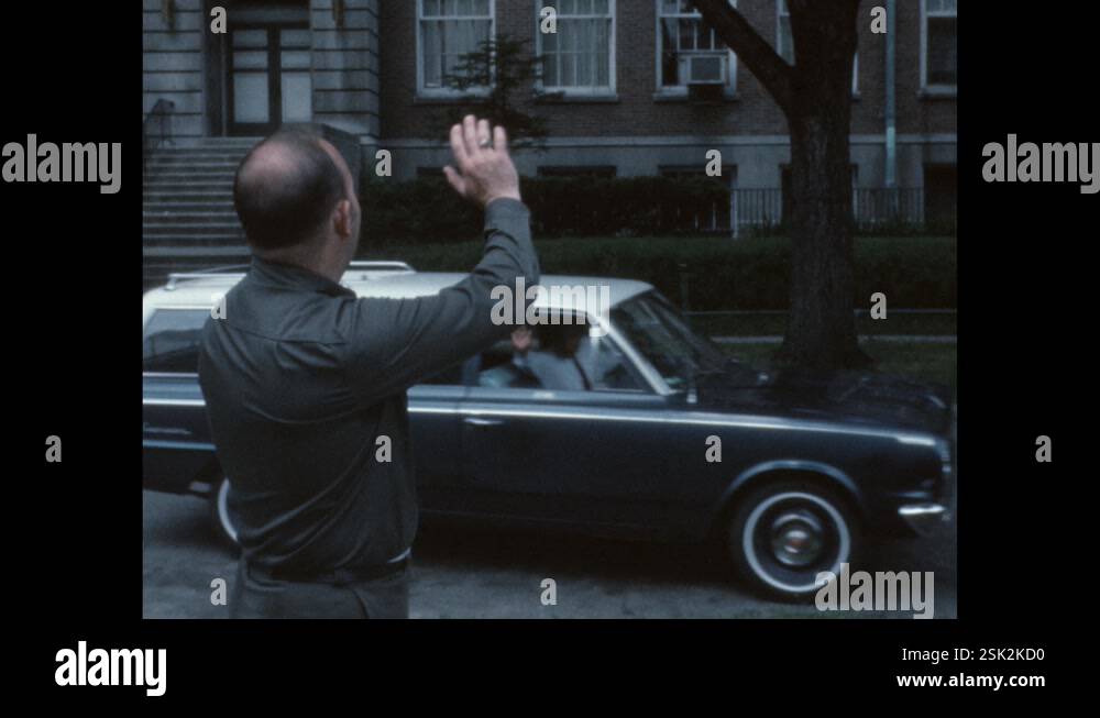 1960s: Man walking along rode waves at person in car, they stop and ...