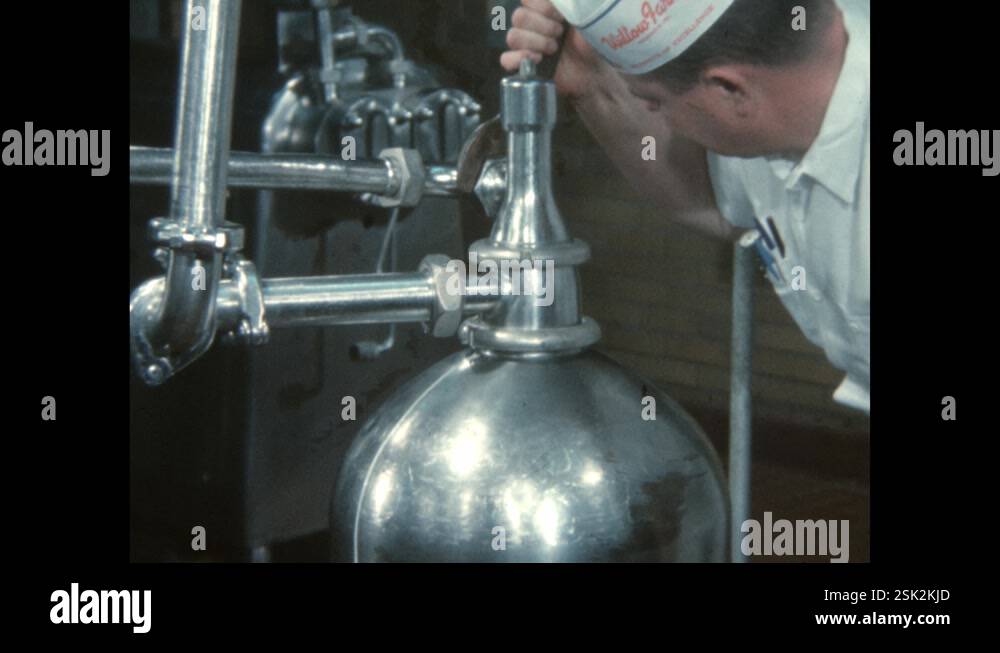 1960s: Uniformed man in boiler room operating equipment with a wrench ...