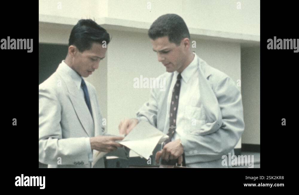 1960s: Men talking outside of building, man takes papers, men shake ...