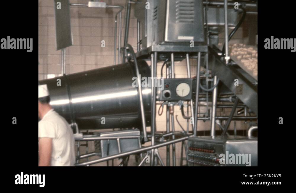 1960s: Cheese curd on conveyor belt, pan across machinery, men wrapping ...