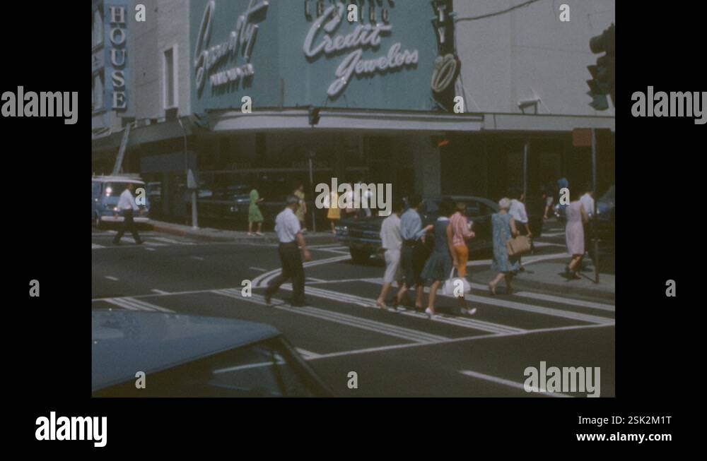 1960s: City intersection, vehicles drive by on street, pedestrians ...
