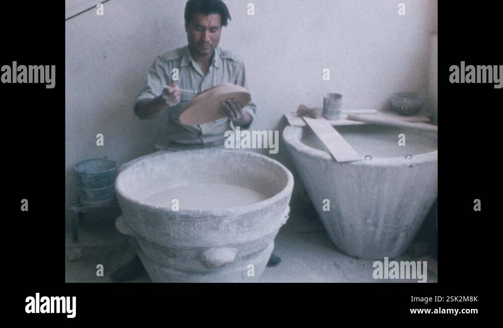1960s Mexico: Man painting then dipping ceramic plate in the vat of ...