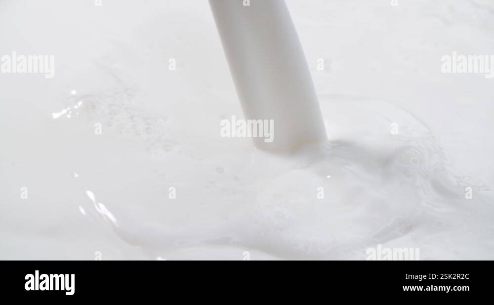 Slow motion shot pouring fresh milk stream and splashing, milk cream ...