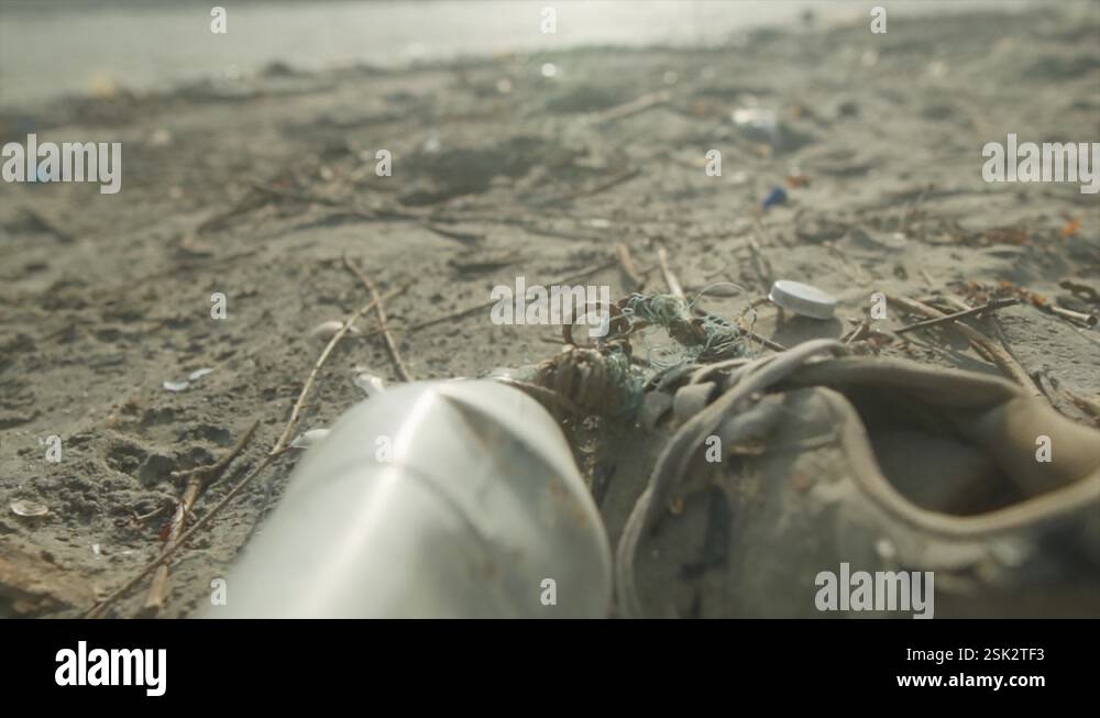 Garbage (shoes and plastic bottles) washed away by the river are lying ...
