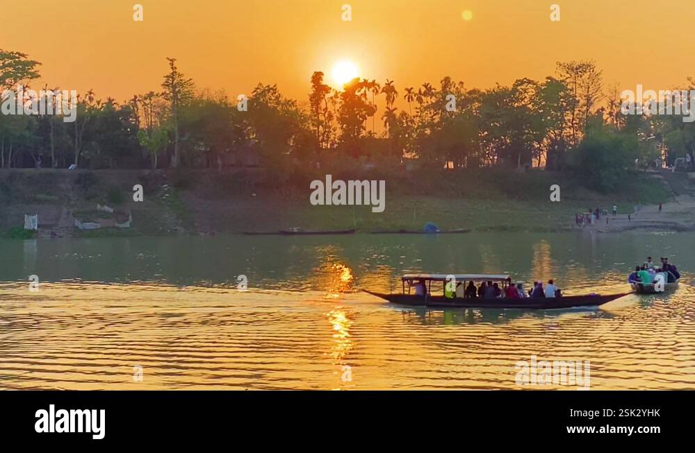 Two passenger boats are passing through the Surma River with people ...