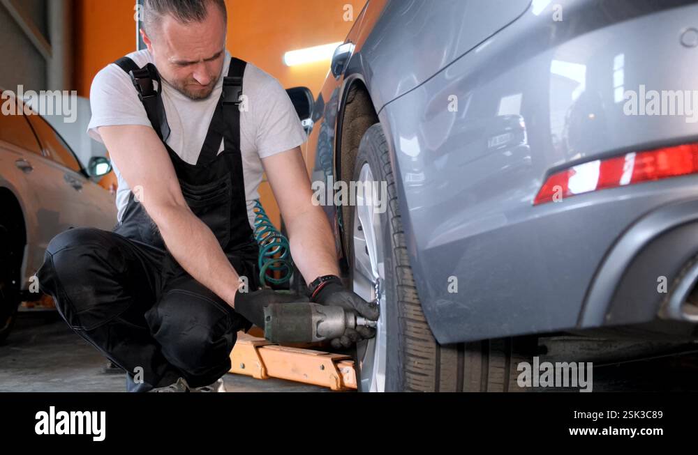 The auto repairer installs or dismantles wheels in the workshop. Car ...