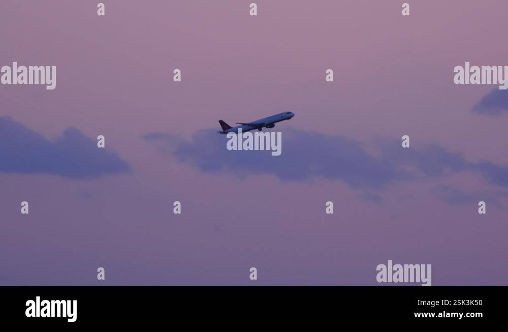 Large airplane takes off into purple red sunset haze sky rising from ...