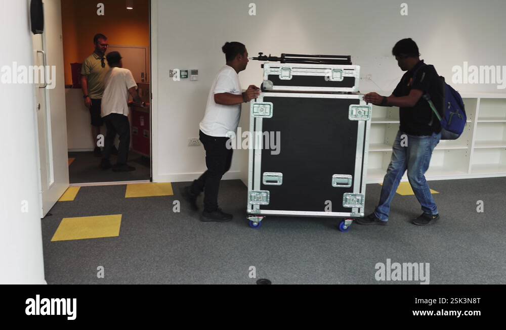 Men moving flight cases and boxes into an office space for a live Stock ...