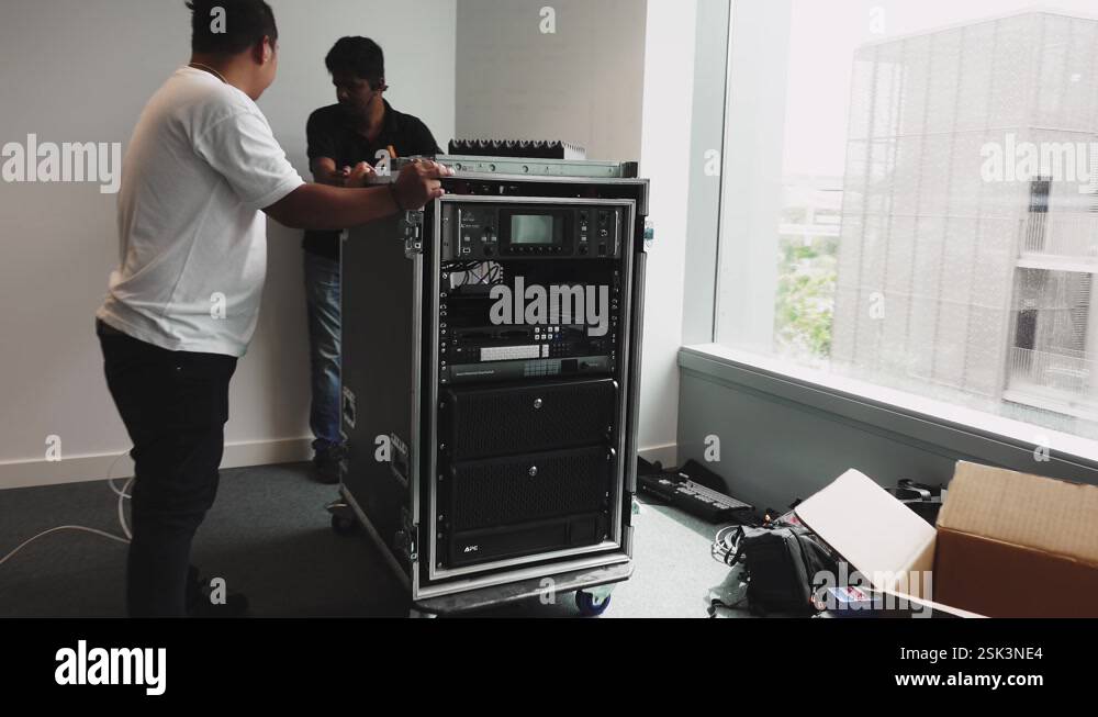 Technicians moving a portable server rack into position in an empty ...