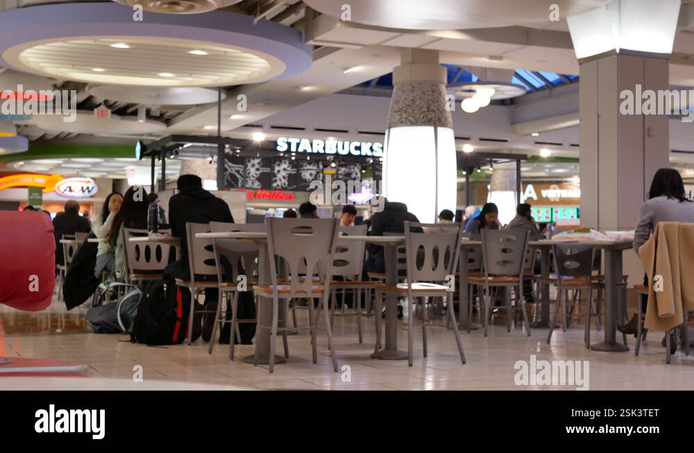 The motion of people enjoying a meal in a modern mall food court ...