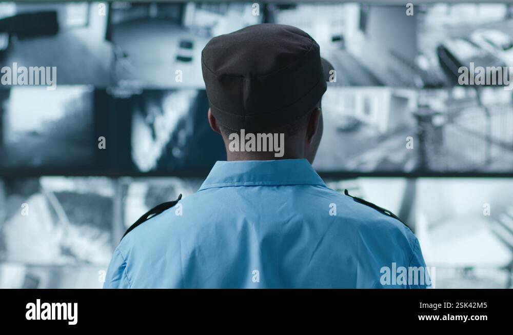 Back view of African-American security guard watching cctv screens in ...