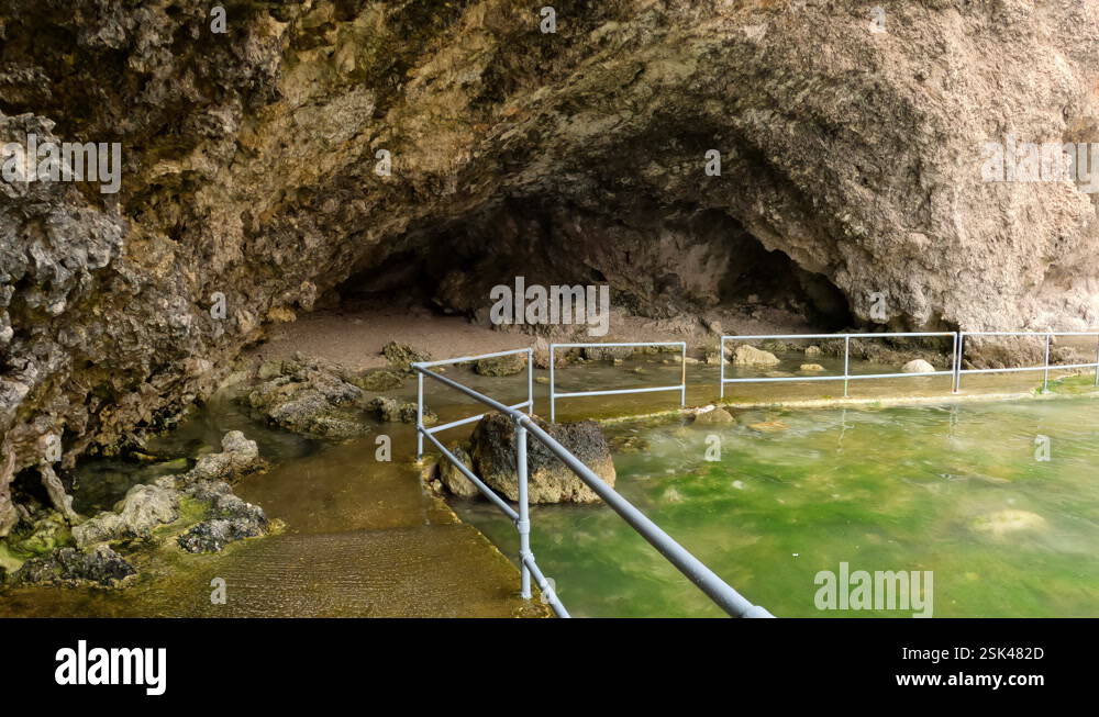 Walk along pathway of hofriet window malta, railing along seaside pool ...