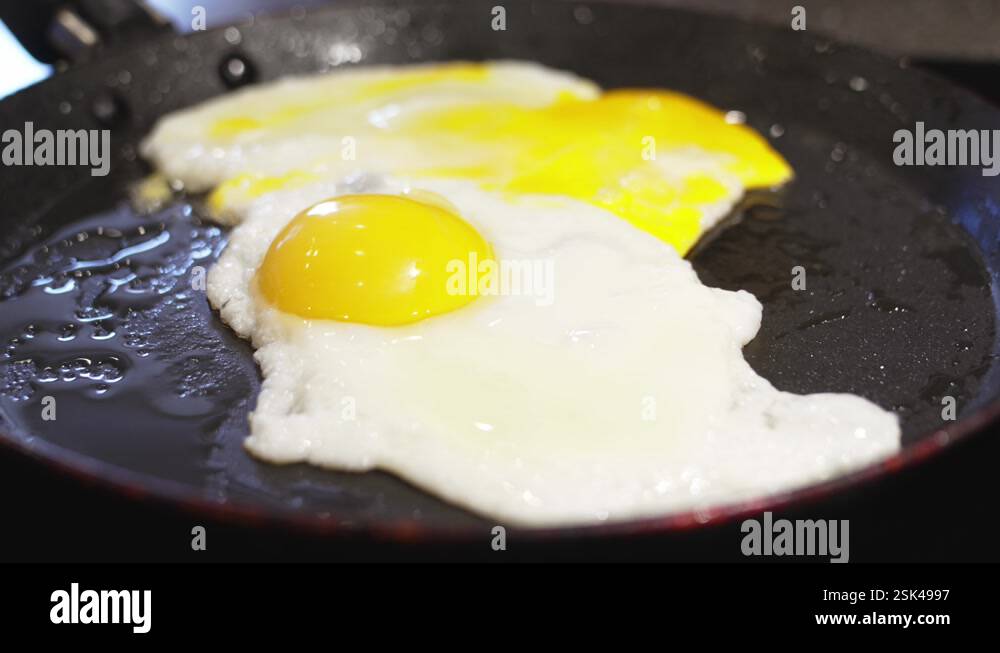 Fry scrambled eggs from two eggs in a pan. In one egg, the yolk bursts ...
