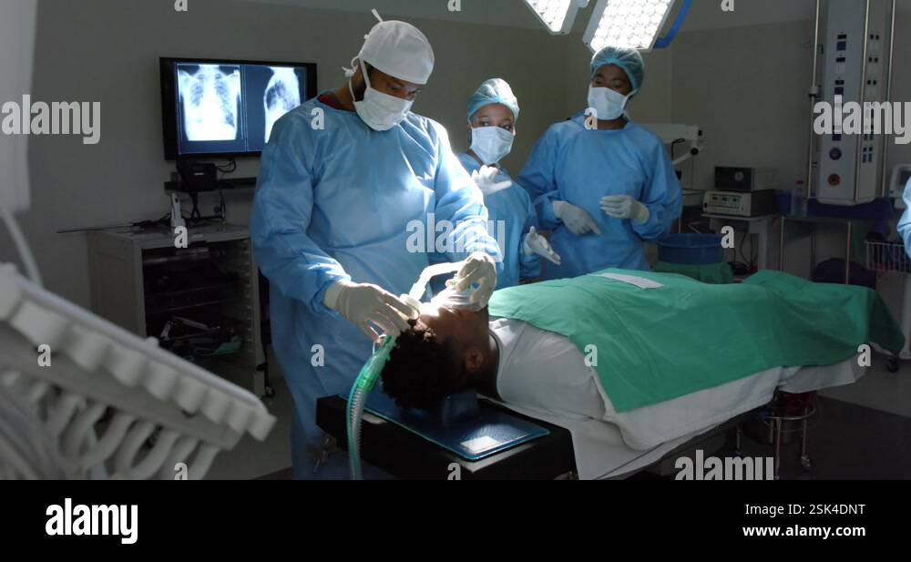 Diverse surgeons giving anesthesia to patient in operating theatre ...