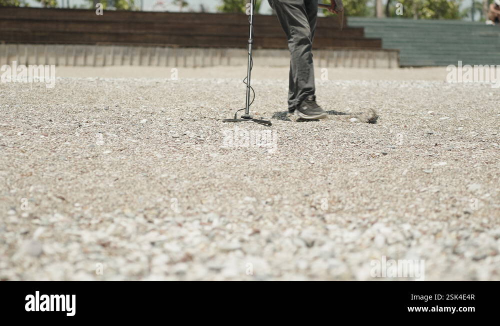 A man with a metal detector is searching for lost items on the rocky ...