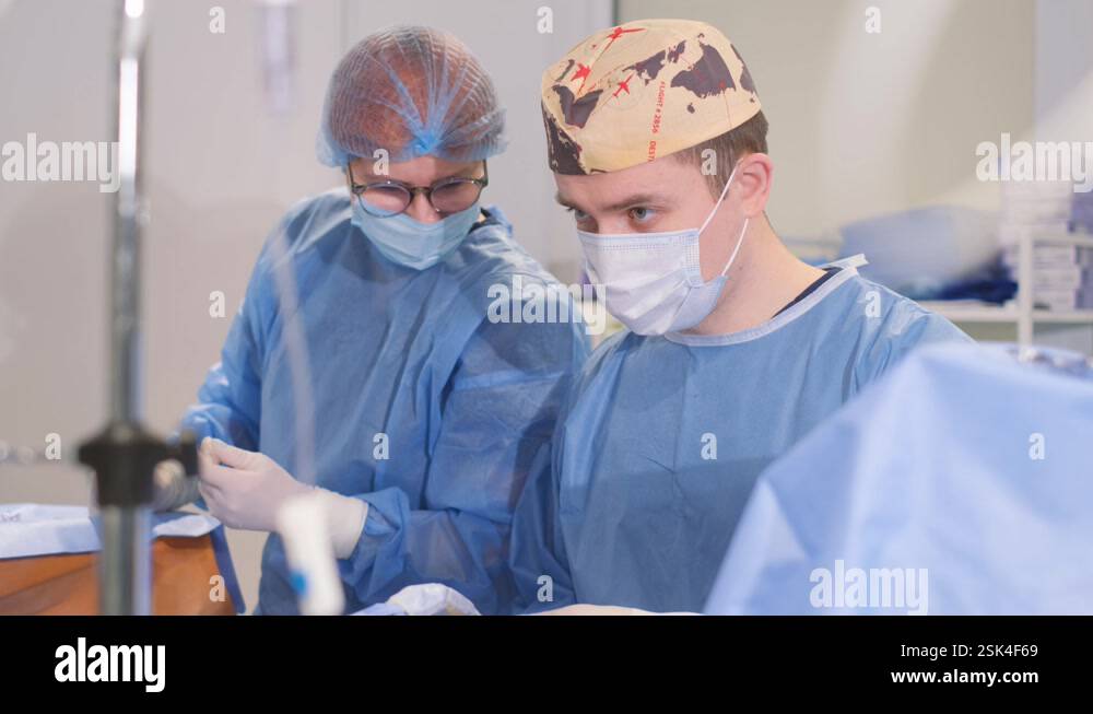 Tired, attentive, focused young surgeon during operation in operating ...