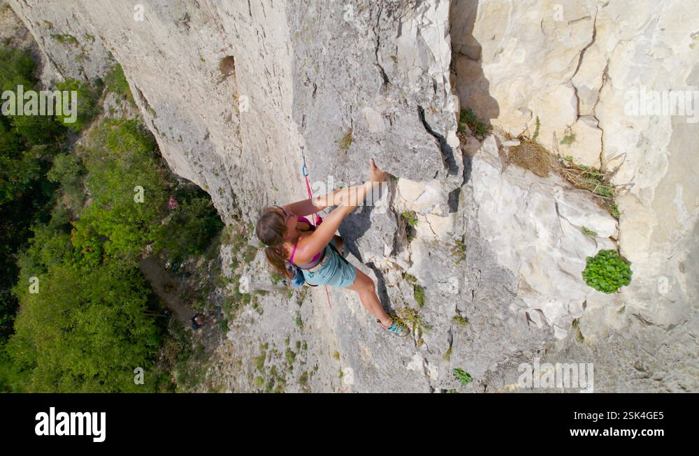 CLOSE UP: Pretty lady lead climbing a challenging route in steep ...