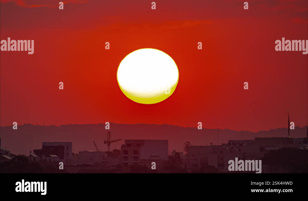 Bright red ball of sun rises above quiet neighborhood casting red ...