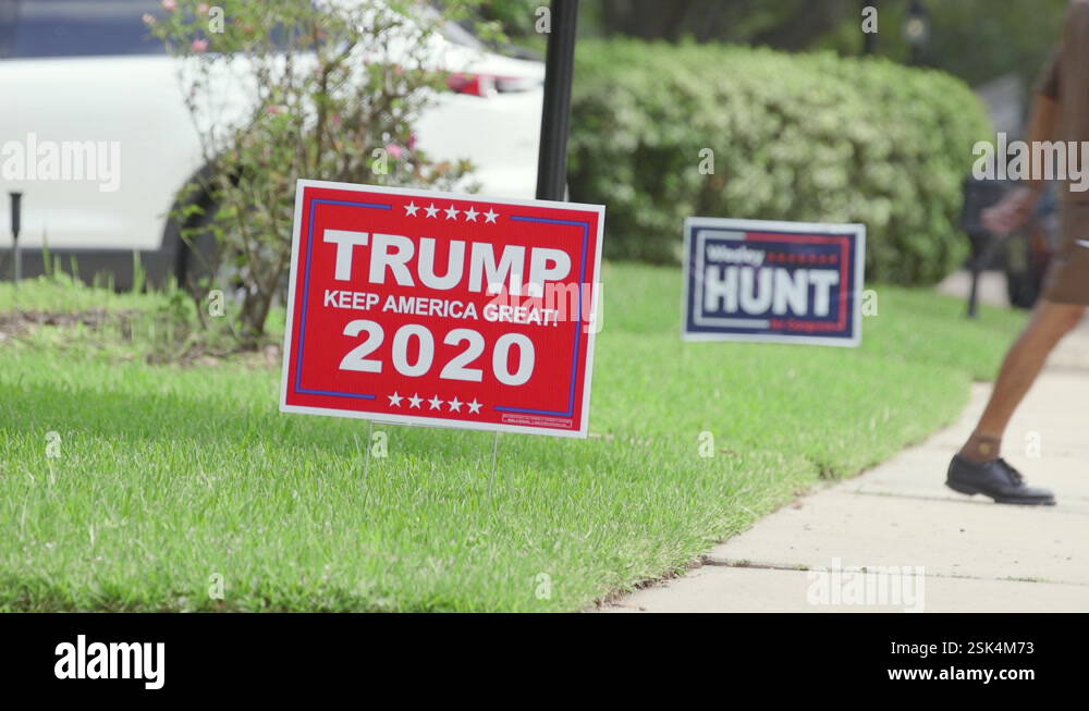A UPS worker walks behind a trump 2020 lawn sign on the grass in front ...