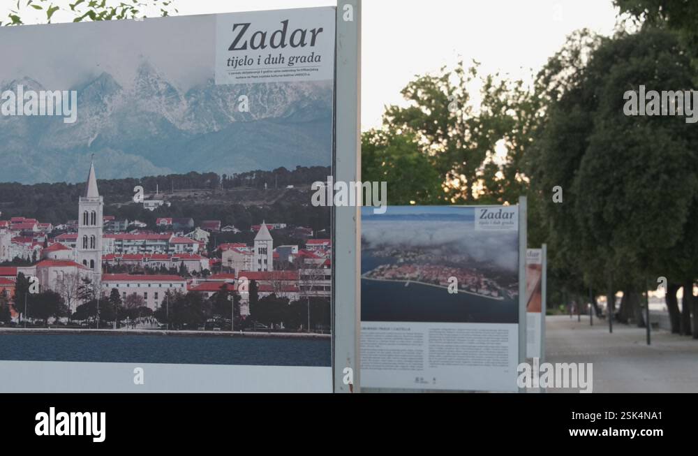 Zadar promenade with info boards, walkway under shade of tree canopy ...