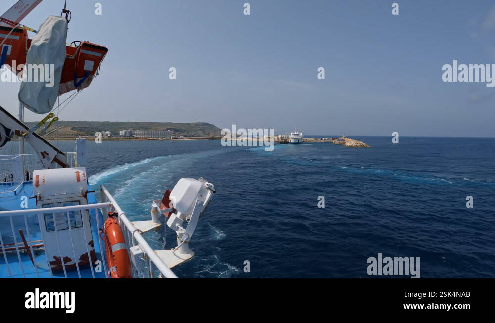 View from back of large ferry boat exiting harbor of island in ocean ...