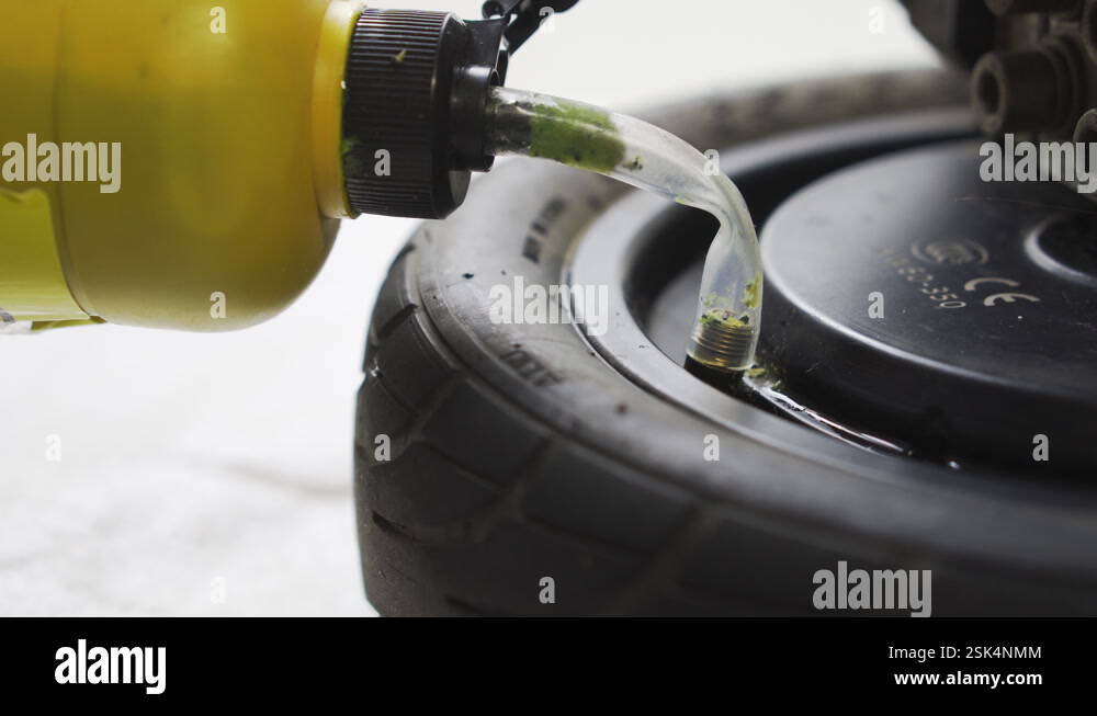 Repairing a punctured wheel with sealant. A man fills a damaged ...
