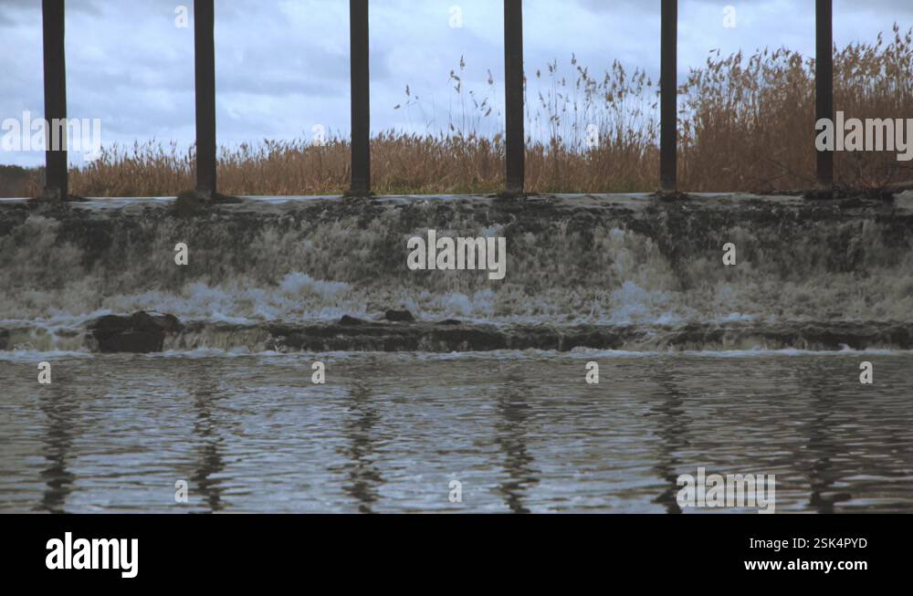 Hydroelectric dam with flowing water through gate. Clear stream calmly ...