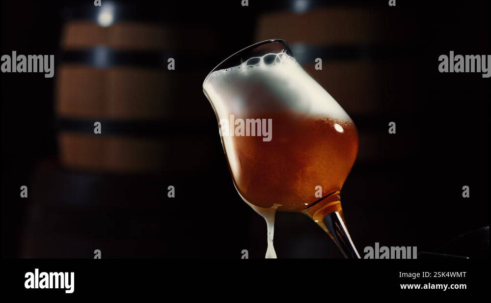 Beer is poured into a glass on a dark background where beer kegs are ...