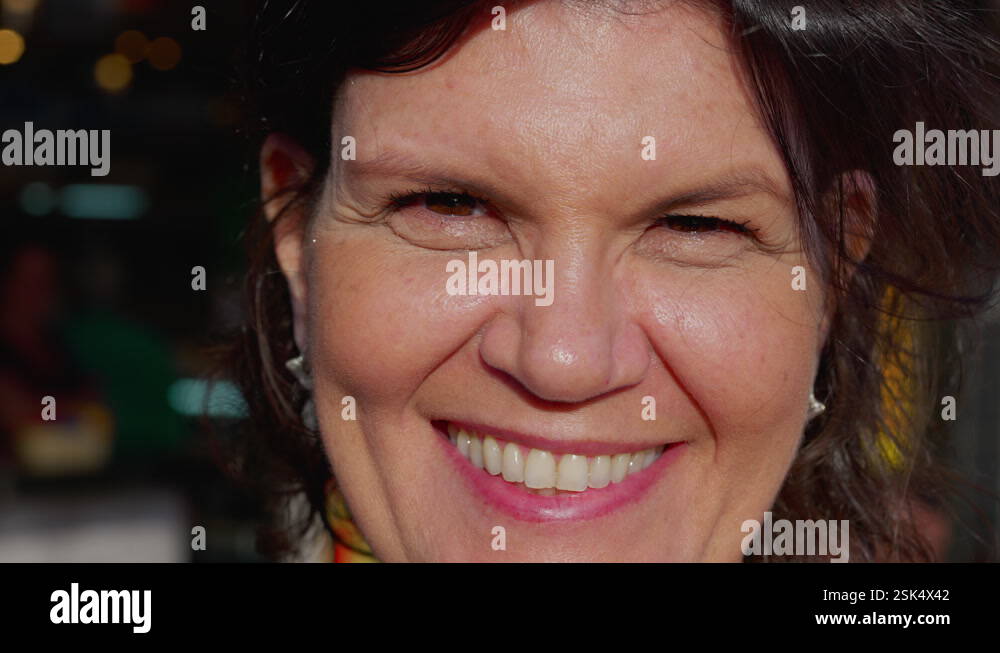 One happy middle-aged woman face smiling at camera in macro close-up ...