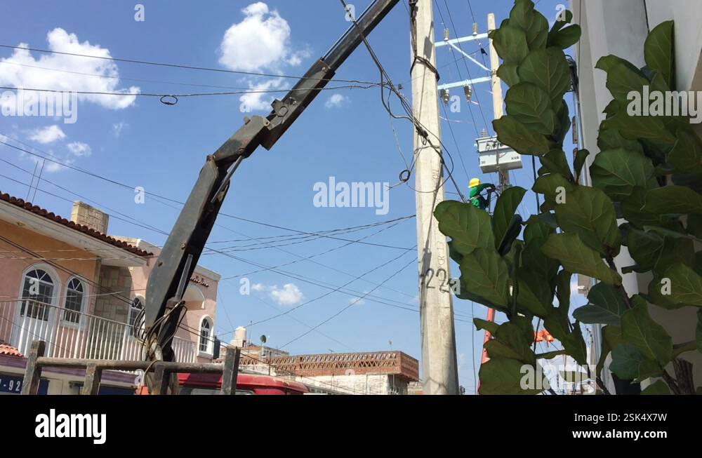 Crane lifting broken concrete power utility pole on busy street, Tuxpan ...