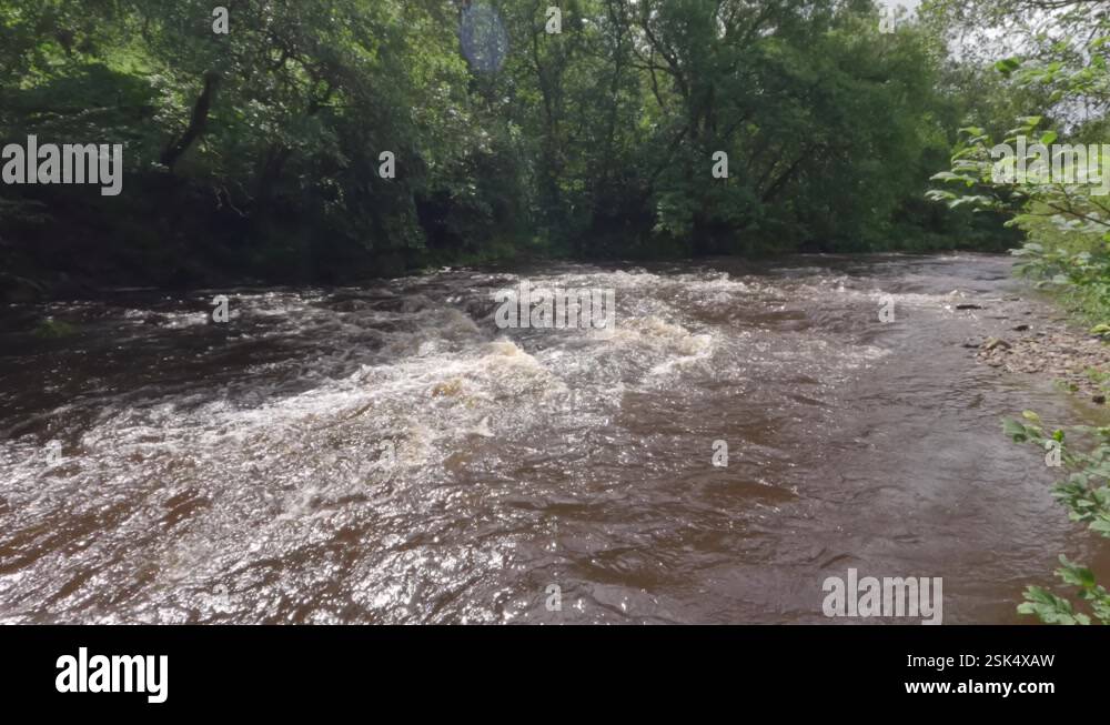 static shot showing a flooded river creating dangerously fast currents ...