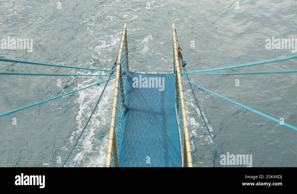 The blue ship's trawl hangs in the sea as it sails through the waves ...