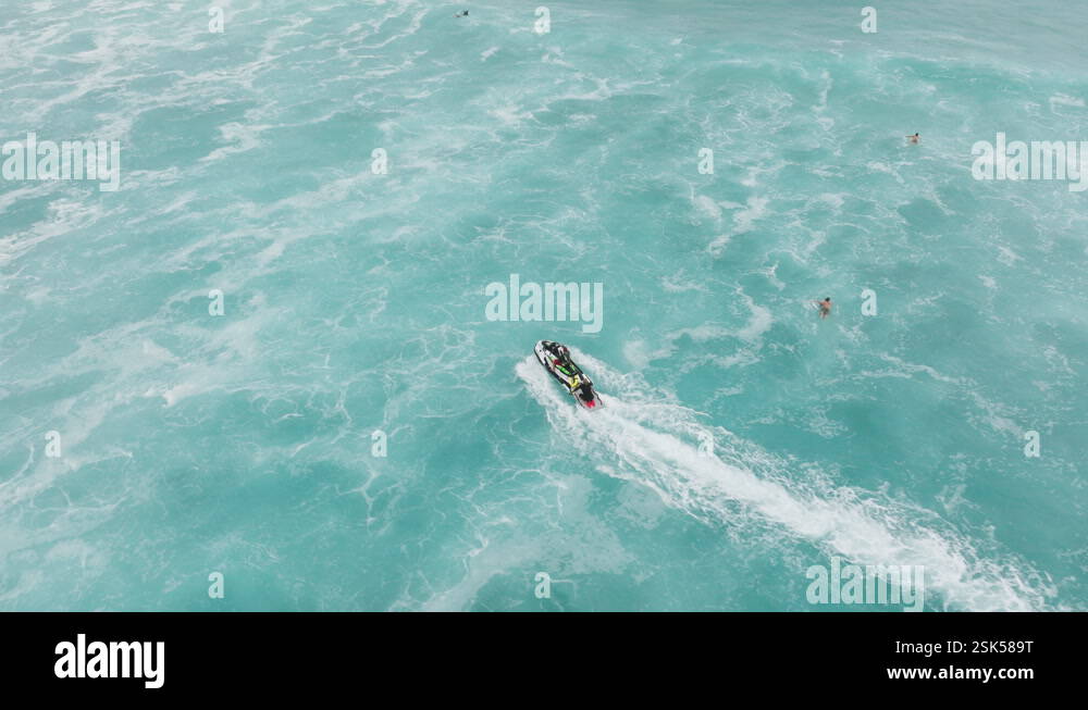 Top down view of Lifeguards riding jet ski to pick up surfers in stormy ...