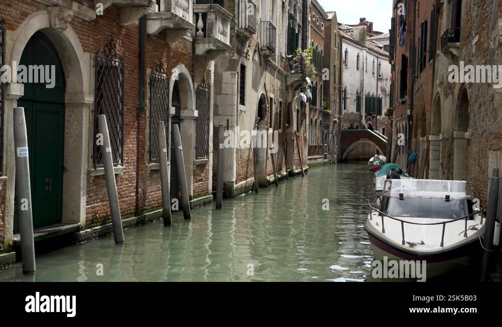 A speed boat moored in a small canal waterway surrounded by beautiful ...
