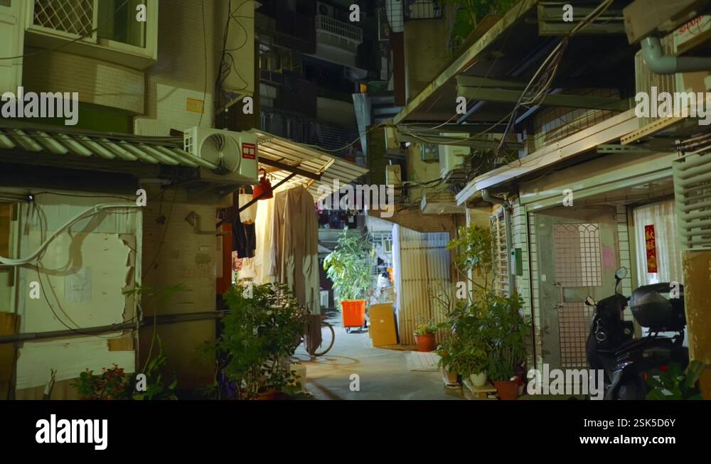Empty alleyway with home entrances and clothes hanging at night in ...