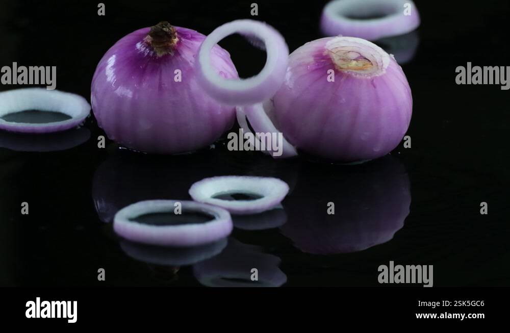 Sliced raw onion rings falling onto whole and chopped onions on ...