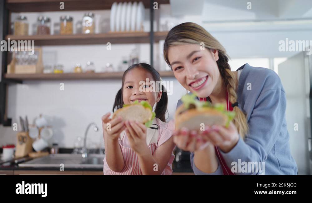 Close up asian mother and daughter in apron holding sandwiches smiling ...