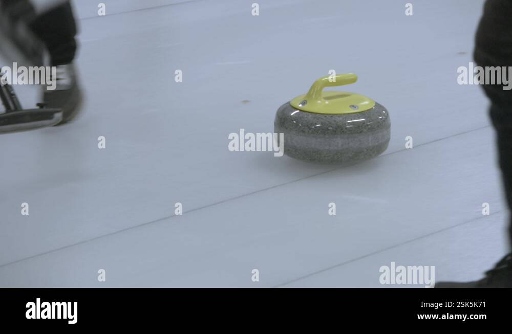 Curling stone sliding over ice sheet and stopping in the house. Two ...