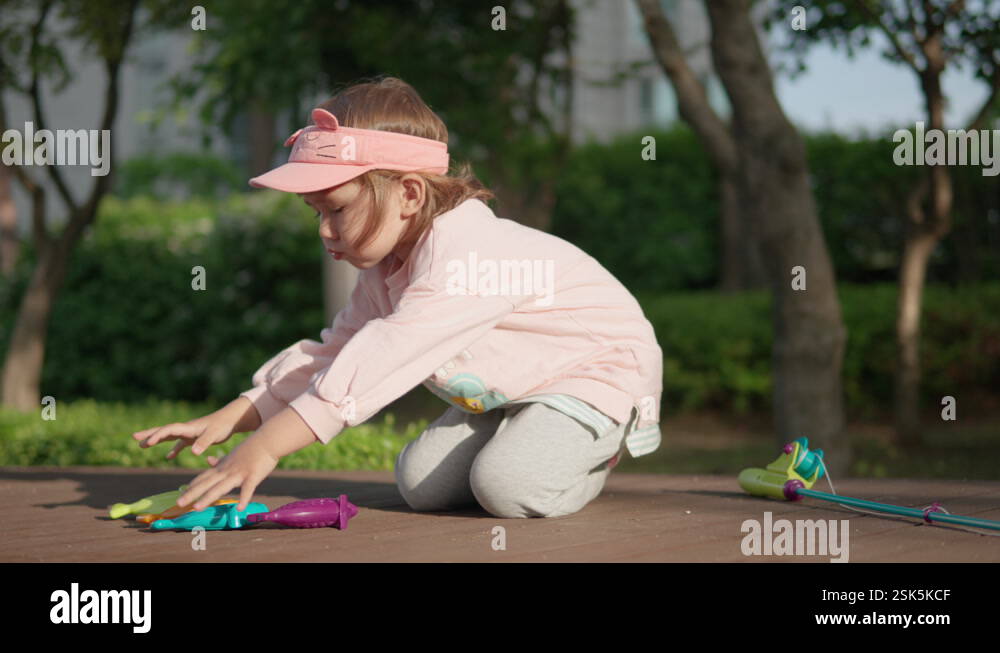 Little Girl Playing Alone With Colorful Fishing Toys On The Ground In ...