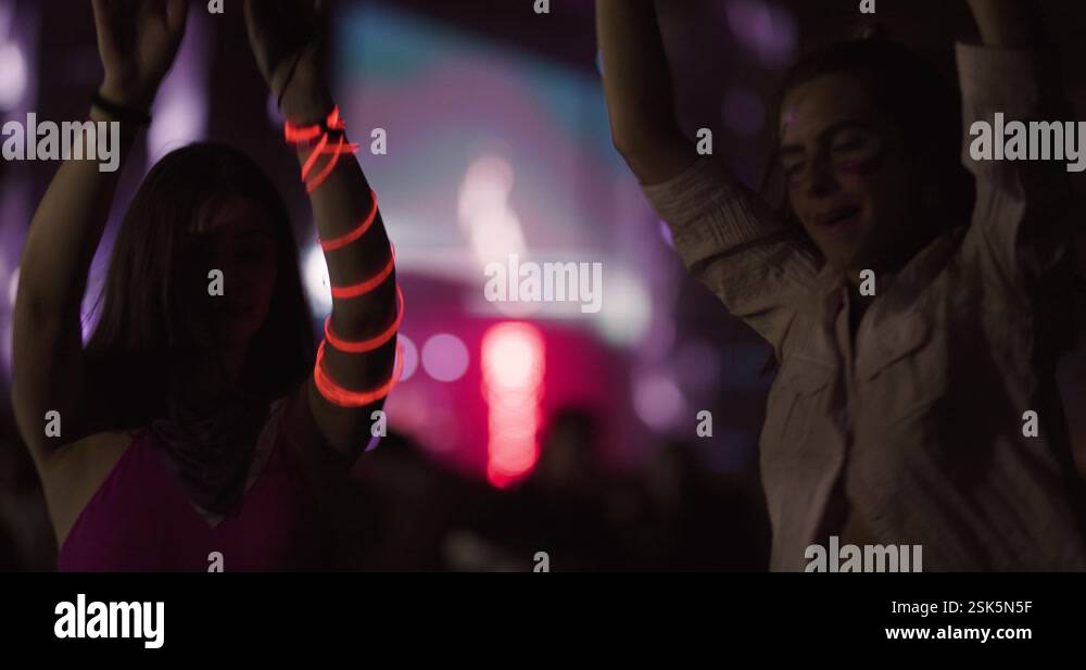 Two Female Friends Dancing Together On Open Space Party With Flashing