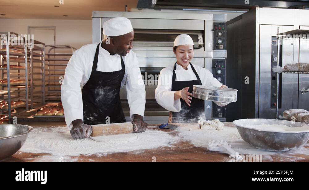 Happy diverse female and male bakers working in bakery kitchen, rolling ...