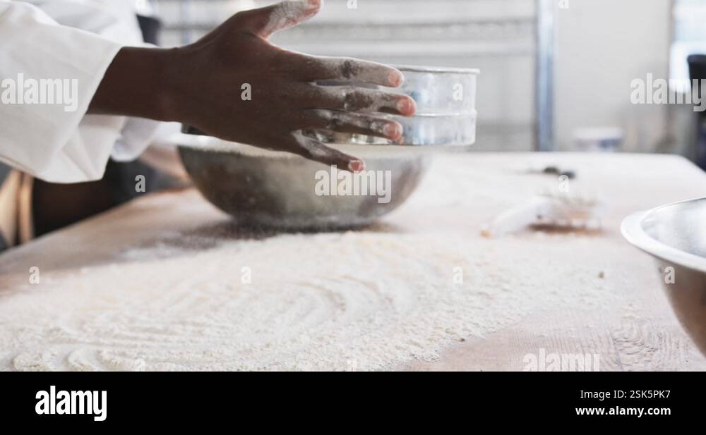 Diverse bakers working in bakery kitchen, pouring flour on counter in ...