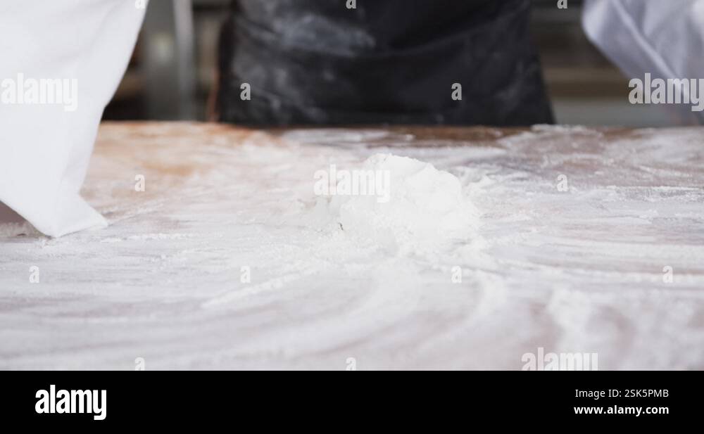 Asian female baker working in bakery kitchen, gathering flour on ...