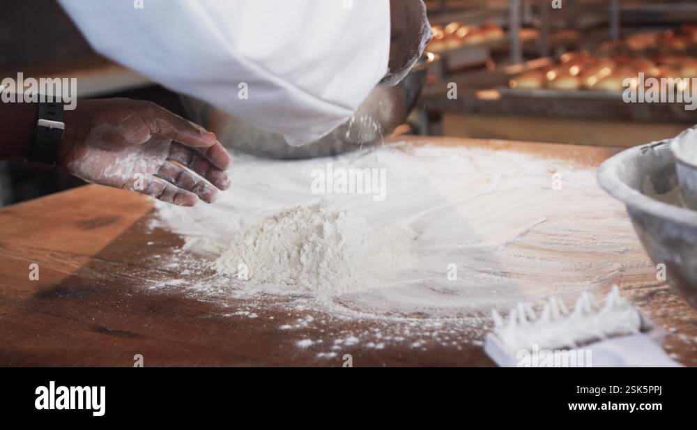 African american male baker working in bakery kitchen, pouring flour on ...