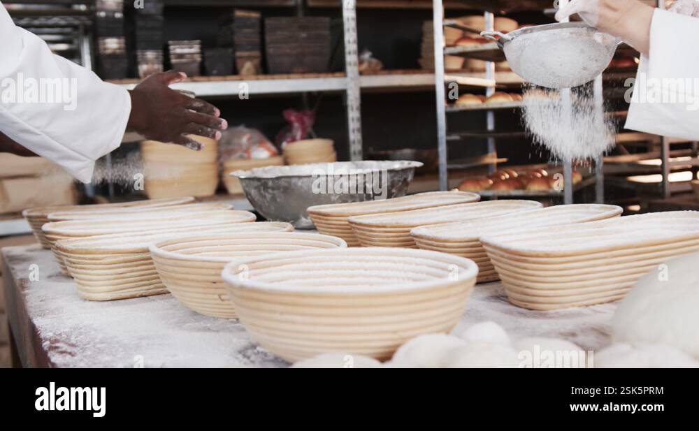 Diverse bakers working in bakery kitchen, pouring flour on baskets in ...
